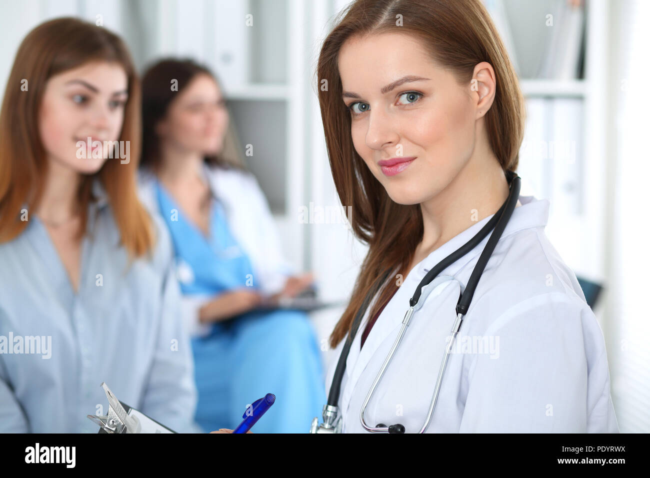 Young beautiful female doctor smiling while consulting her patient ... Young beautiful female doctor smiling while consulting her patient ...