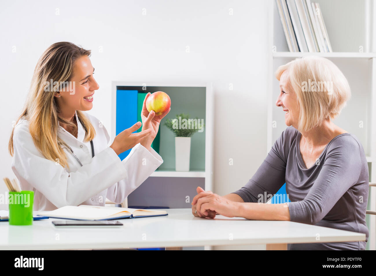 Female doctor is giving advice about eating healthy food to her senior ...