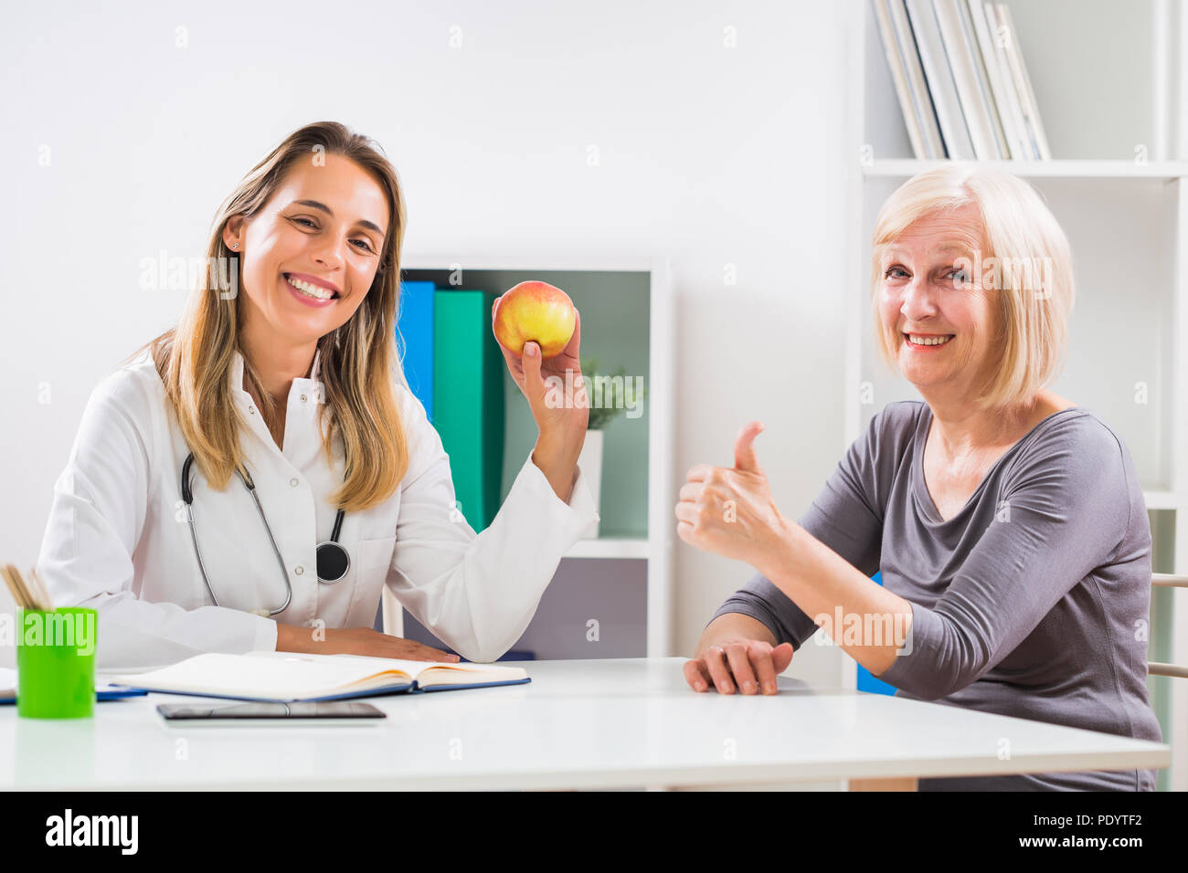 Female doctor is giving advice about eating healthy food to her senior ...