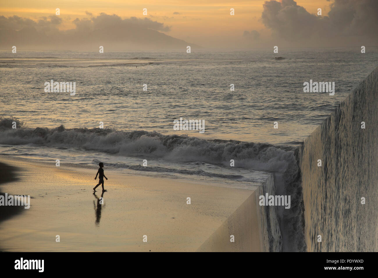 Silhouette of a boy on the beach at sunset. Bending inception effect ...