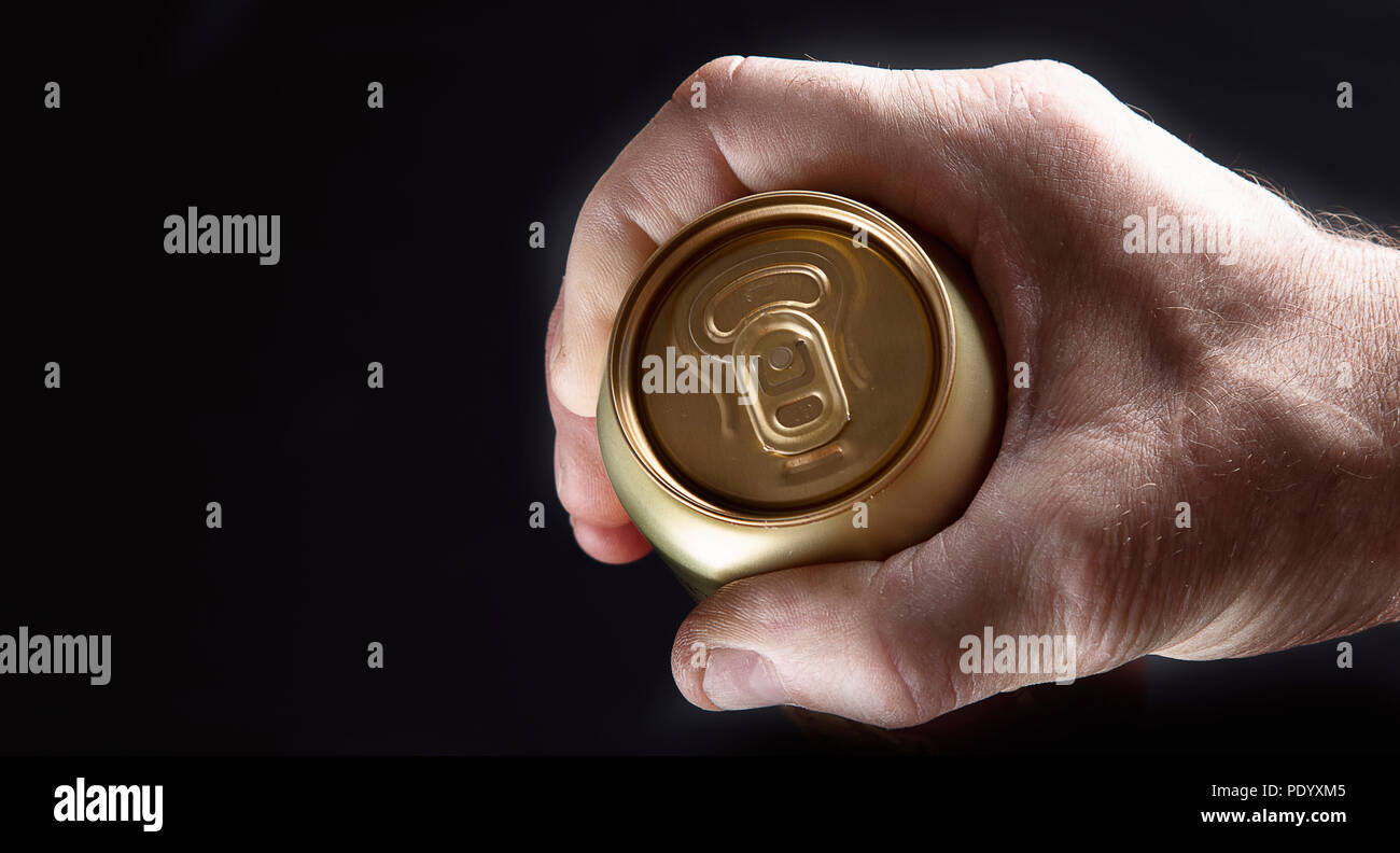 Beer can in hand on black background Stock Photo - Alamy