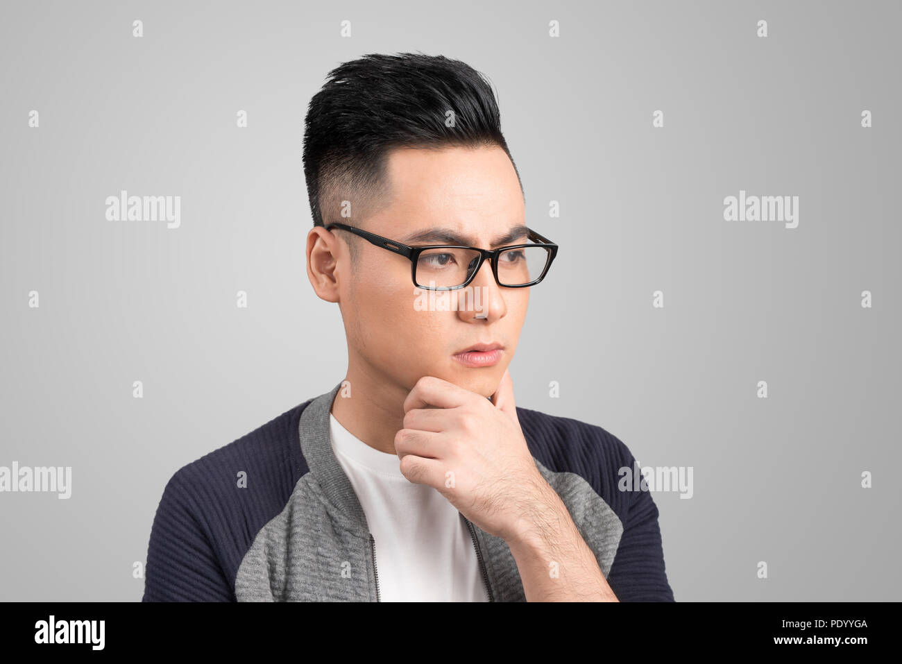 A portrait of a young asian man thinking looking down isolated over ...