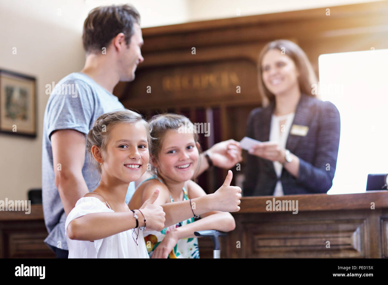 Happy family checking in hotel at reception desk Stock Photo - Alamy