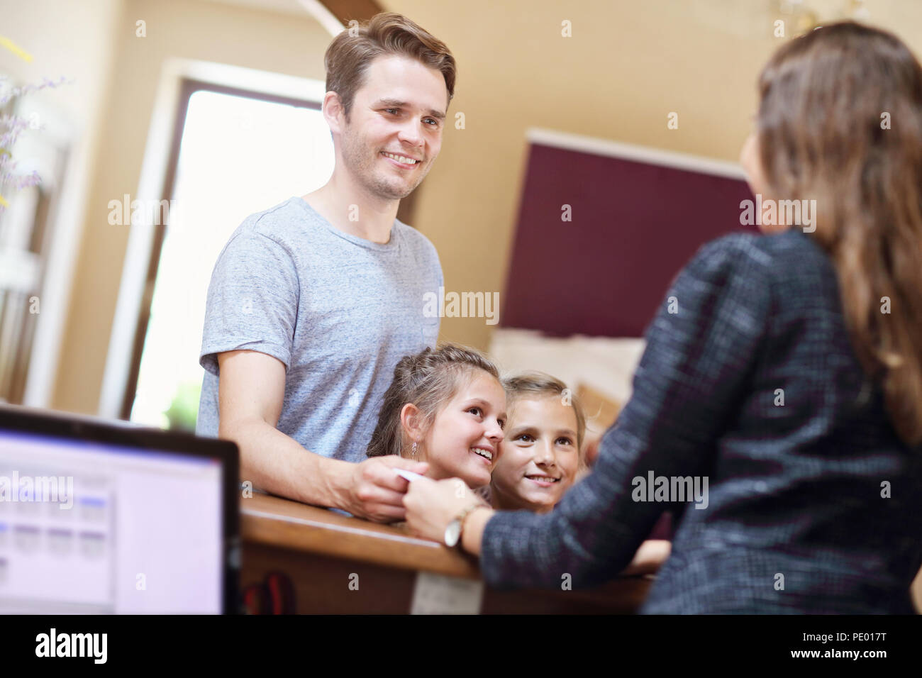 Happy family checking in hotel at reception desk Stock Photo - Alamy