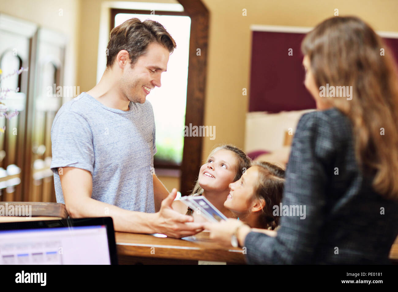 Happy family checking in hotel at reception desk Stock Photo - Alamy