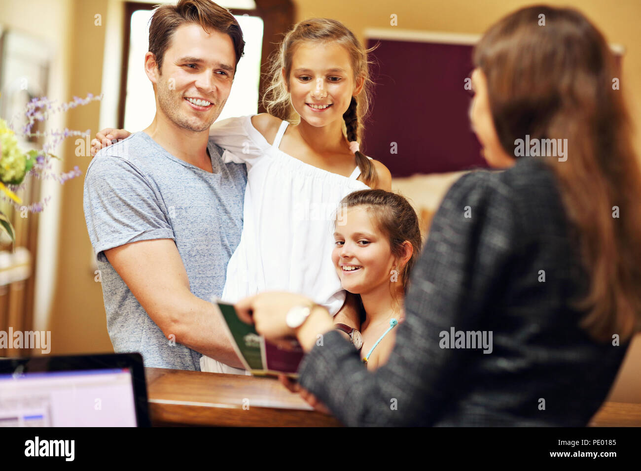 Happy family checking in hotel at reception desk Stock Photo - Alamy