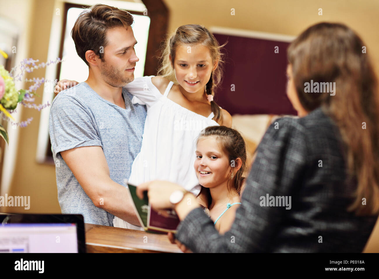 Happy family checking in hotel at reception desk Stock Photo - Alamy