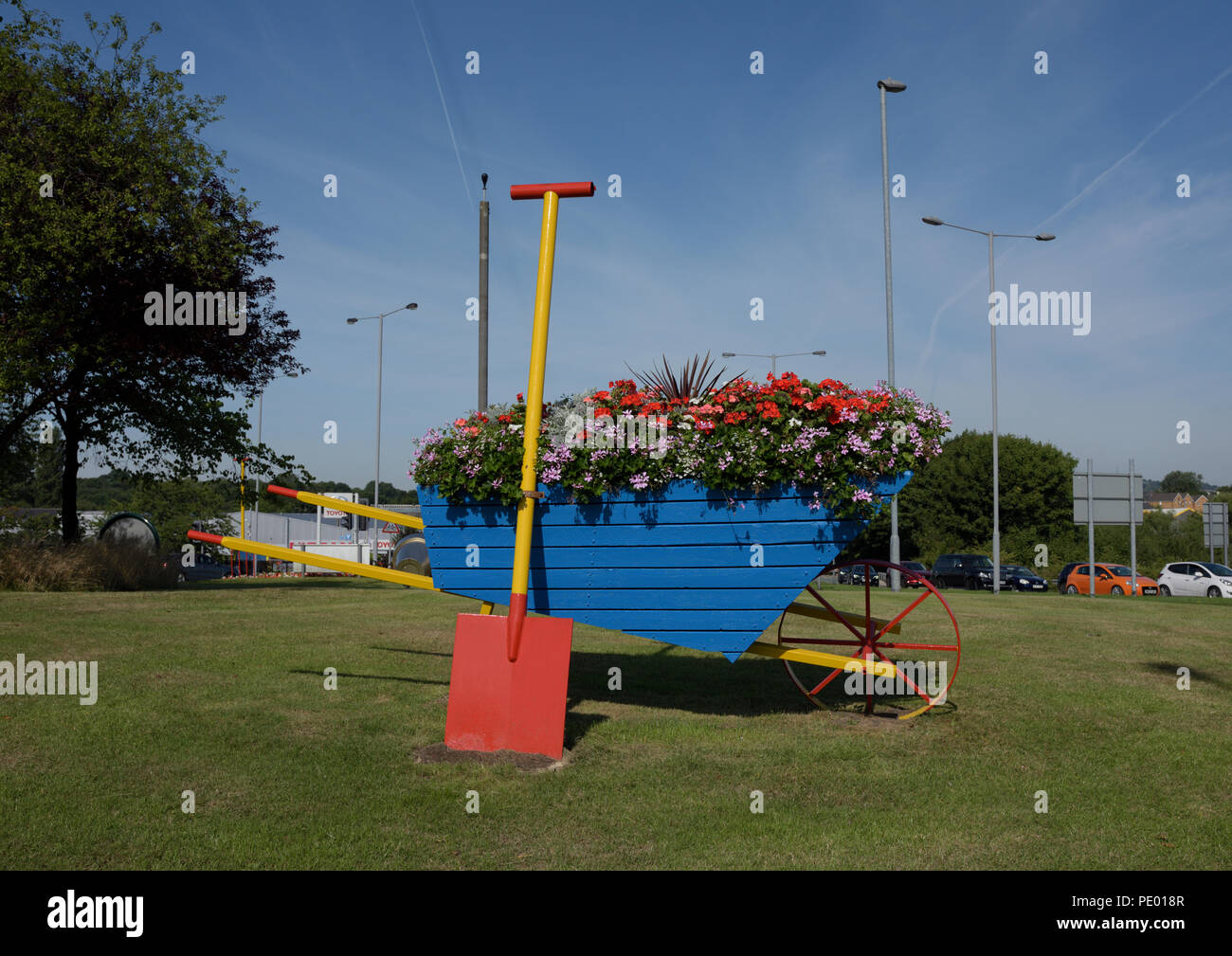 Bury in bloom flower display, giant wheelbarrow and spade on traffic ...