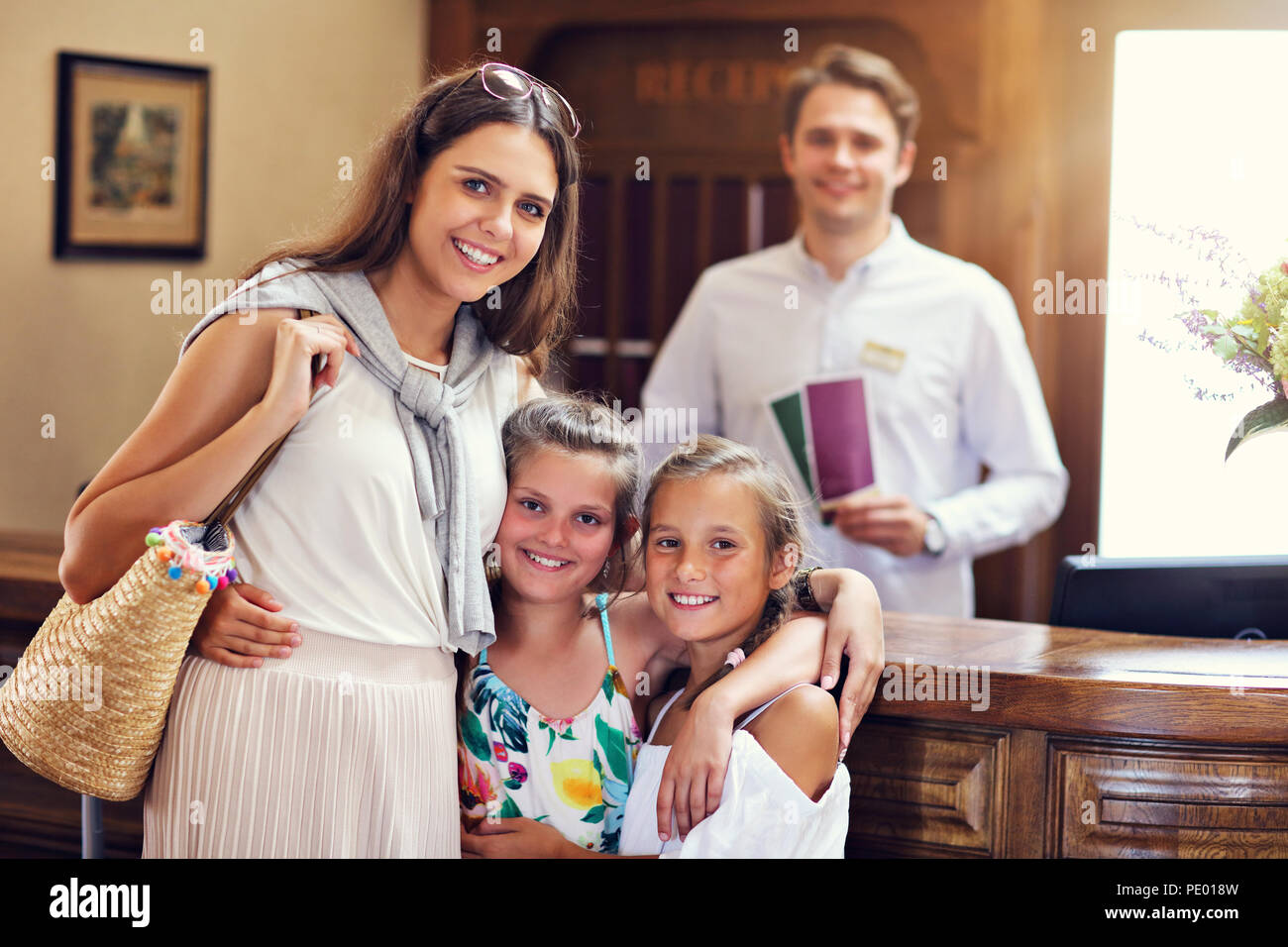 Happy family checking in hotel at reception desk Stock Photo - Alamy