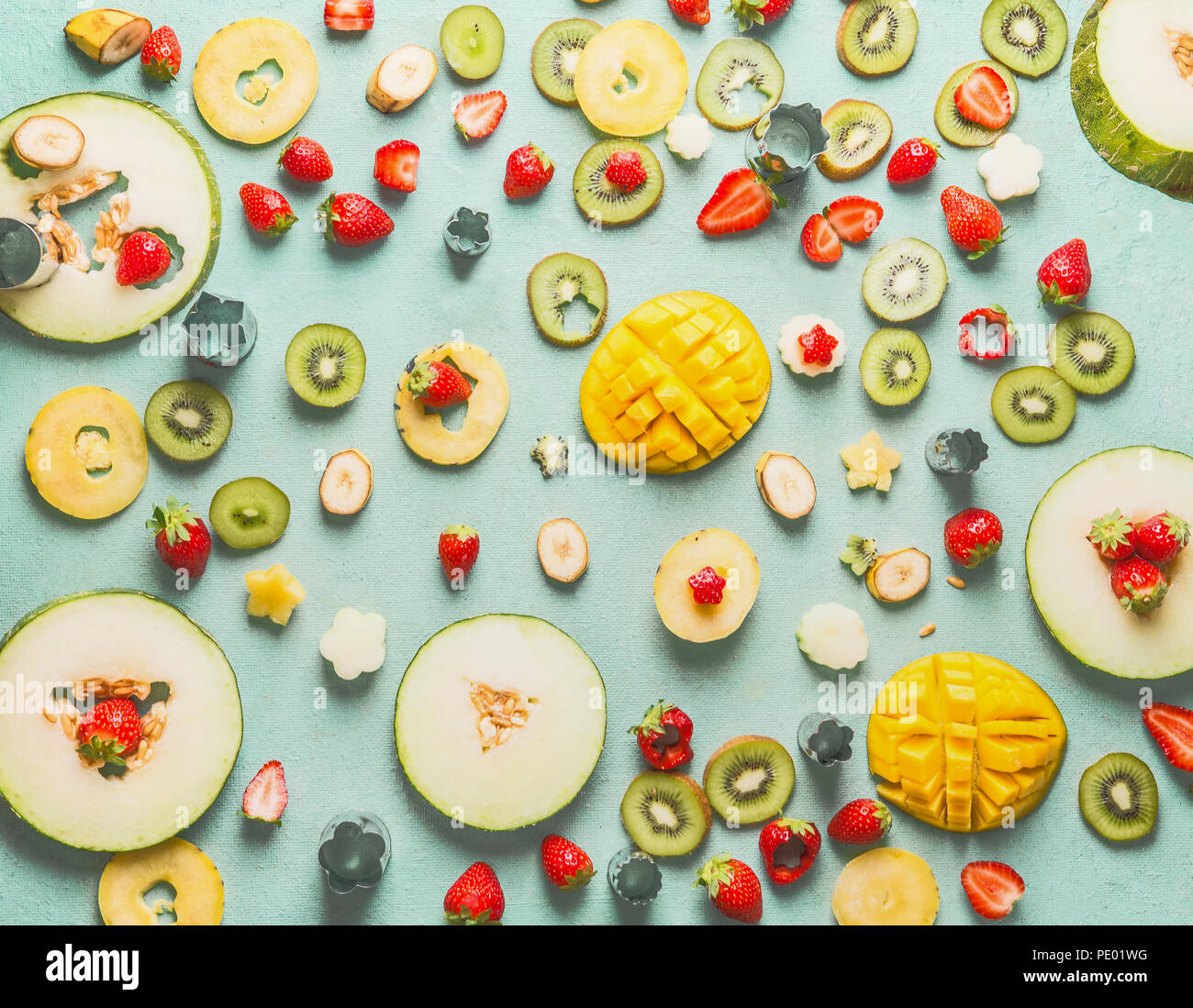 Various sliced fruits and berries on light blue background, top view ...