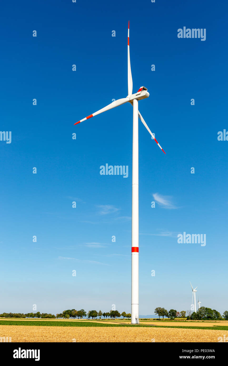 white wind turbines with red stripes generating electricity on a bright ...
