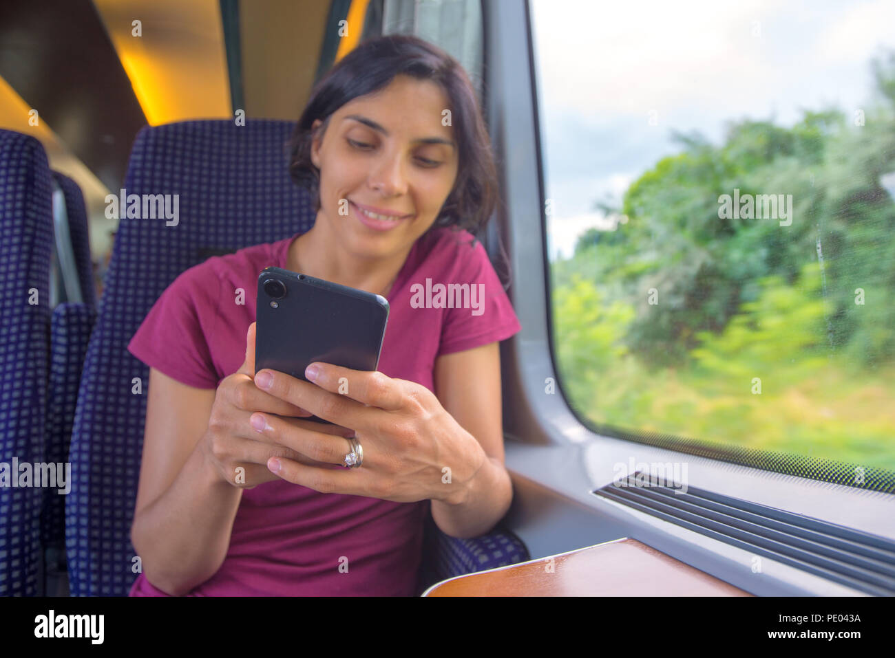 Woman texting on her phone during her trip in train Stock Photo - Alamy