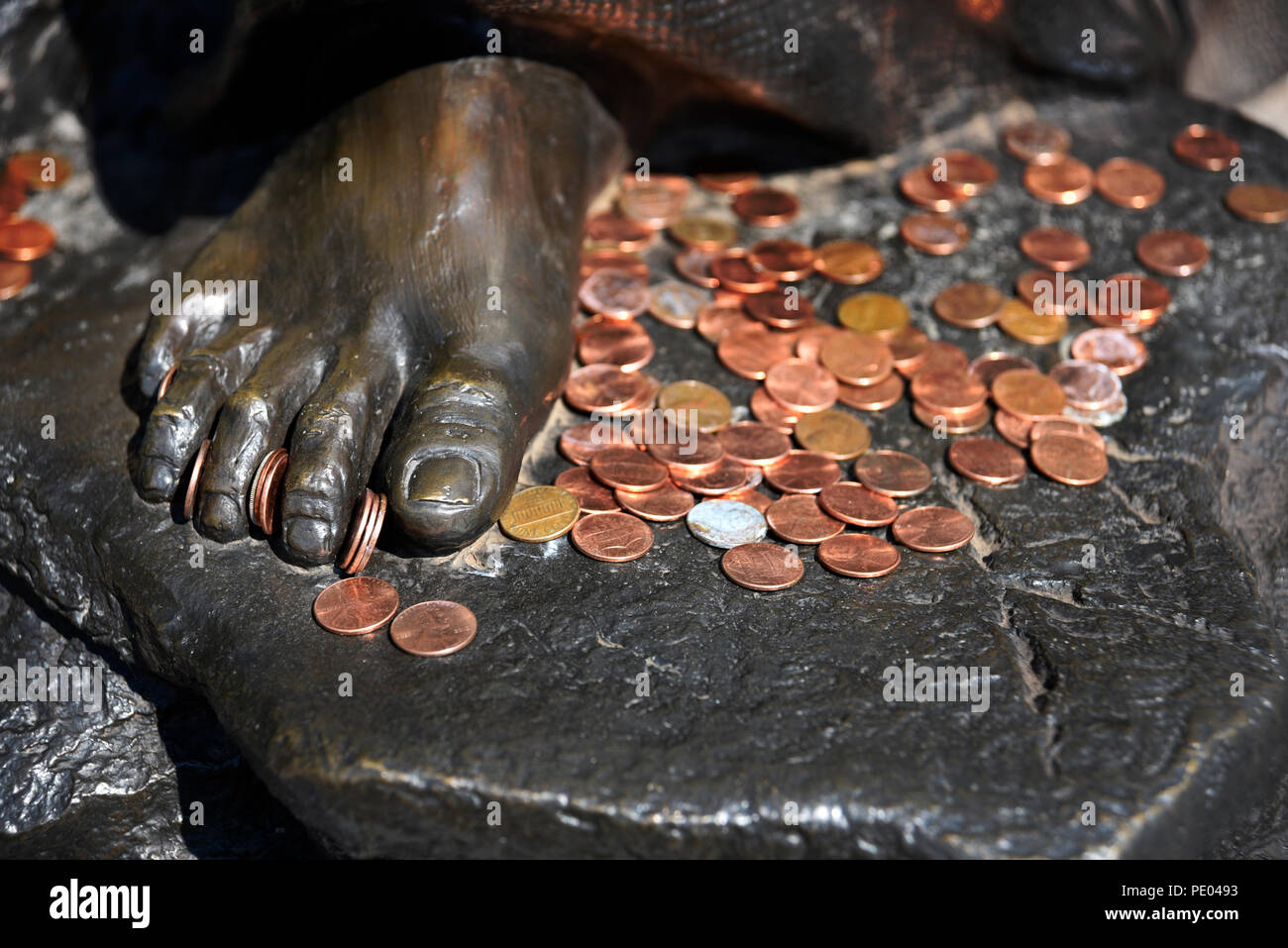 Coins left by visitors at the base of a statue of St. Francis of Assisi ...