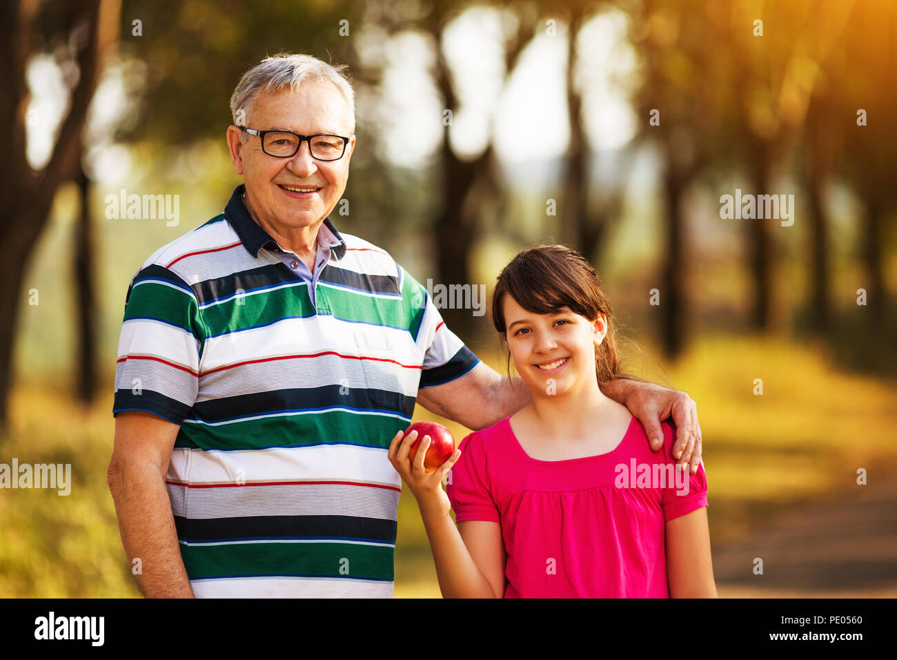 Portrait of grandfather and granddaughter holding apple in nature.Image ...