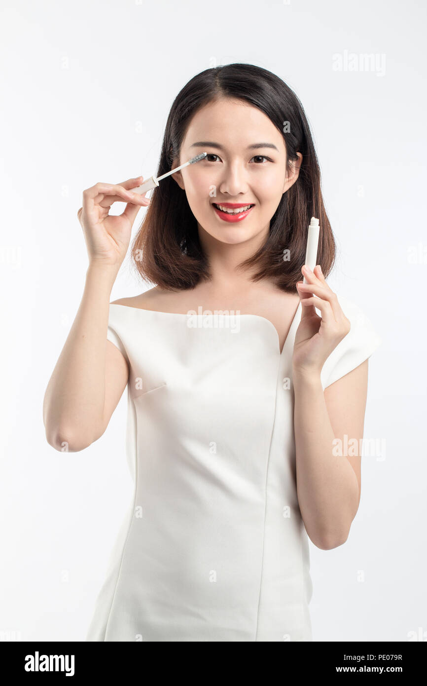 Chinese woman putting mascara on eyelashes on gray background Stock ...
