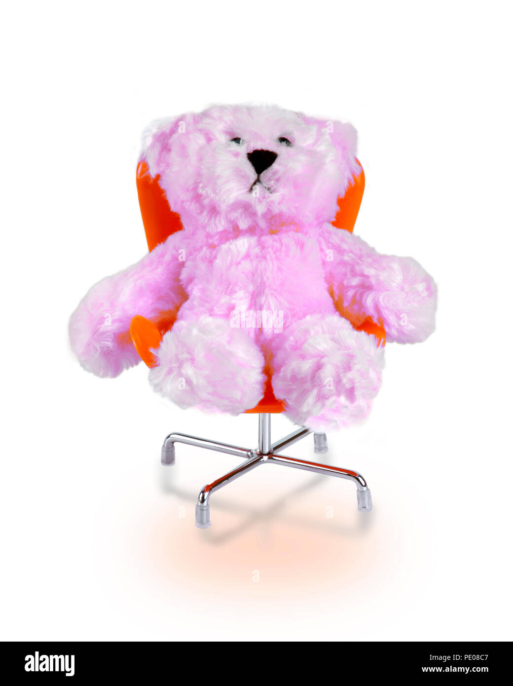 Little pink bear doll sitting in orange chair on white background Stock ...