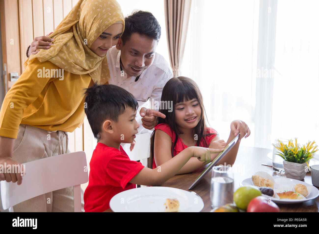kids and parent using tablet pc at dining room together Stock Photo - Alamy