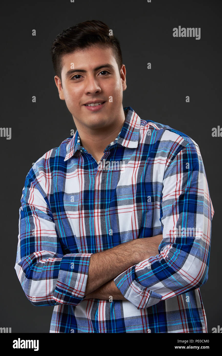 Young latin man with crossed arms in dark studio background Stock Photo ...