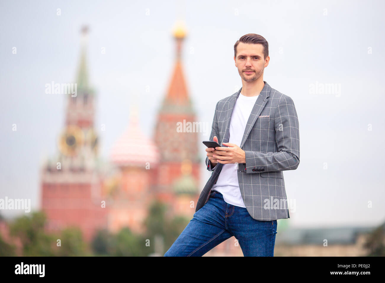 Young urban man with smarphone outdoors on background of St Basils ...