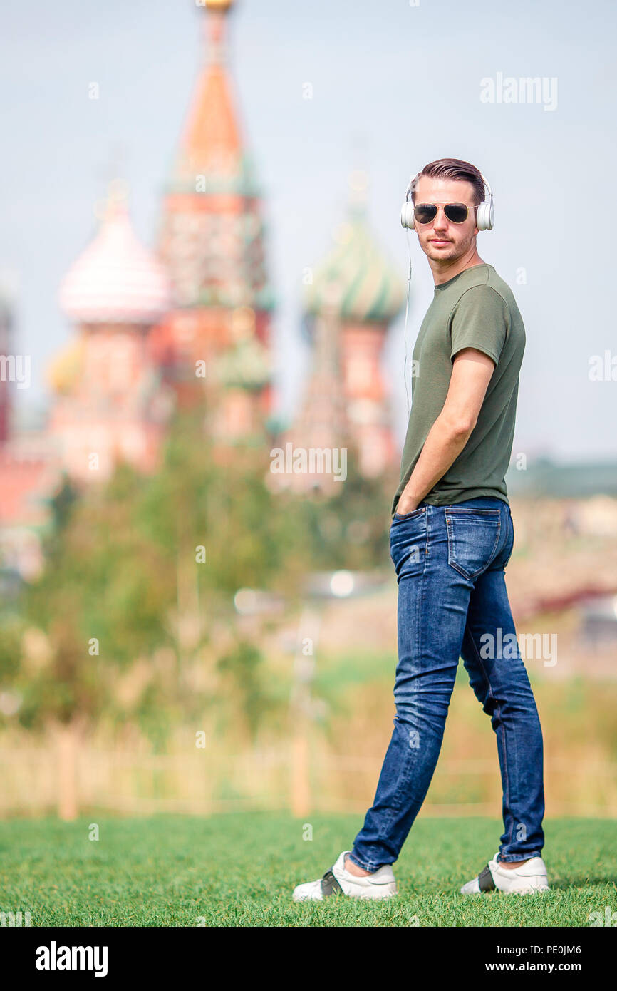 Portrait of young urban man listening the music outdoors on background ...