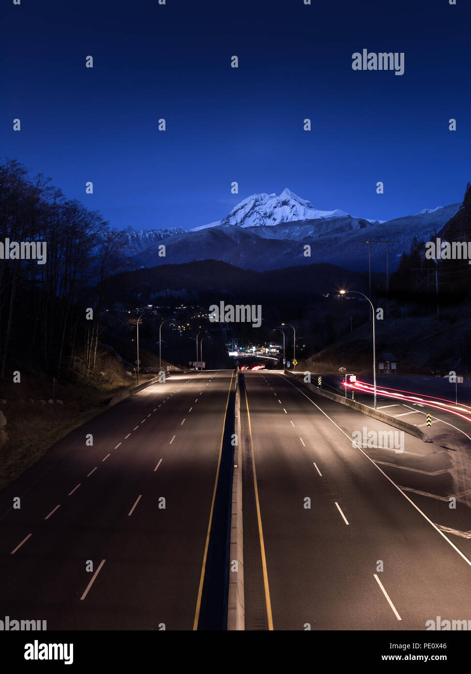 Highway with a snowy mountain peak in the background Stock Photo - Alamy