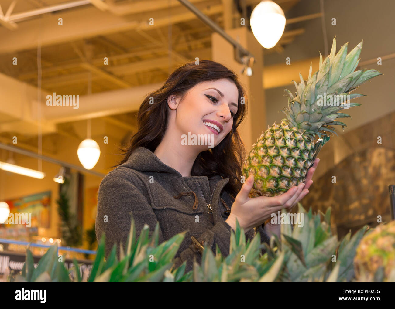 Young woman in the produce section of a grocery store, smiling, while ...