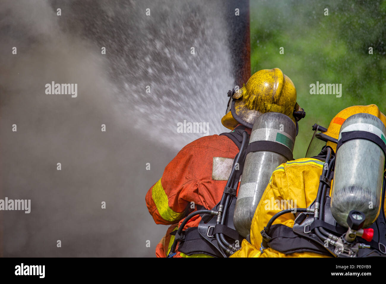 close up action of two firefighters water spray by high pressure nozzle ...