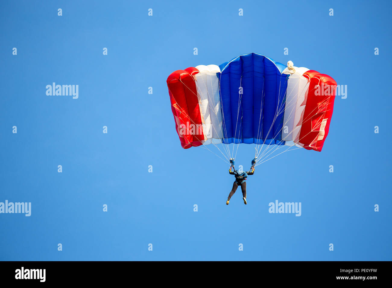 isolated skydiver in colorful parachute gliding after free fall jump ...