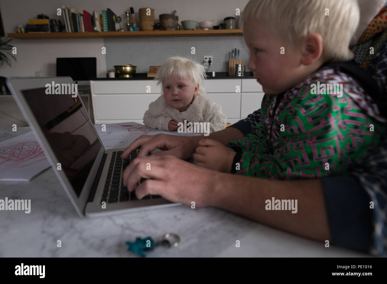 Father using laptop with his kids in living room Stock Photo - Alamy