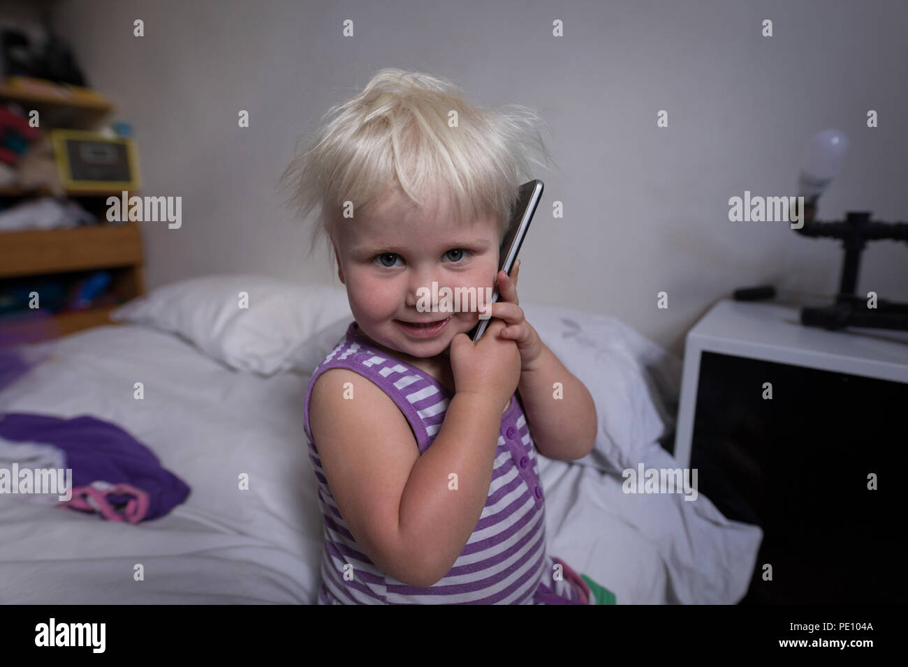 Baby girl talking on mobile phone in bedroom Stock Photo - Alamy