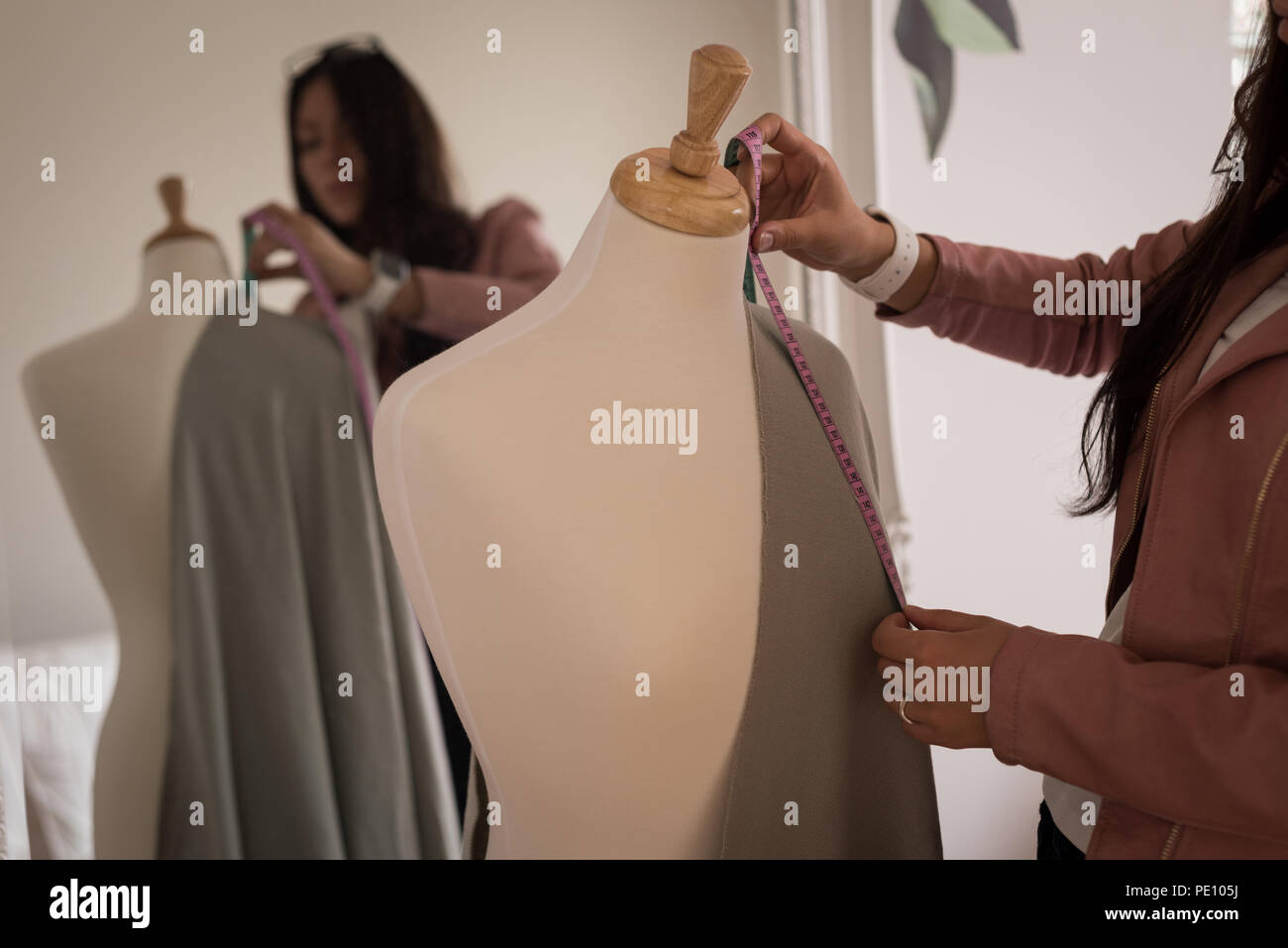 Fashion designer measuring the fabric on dressmakers model Stock Photo ...
