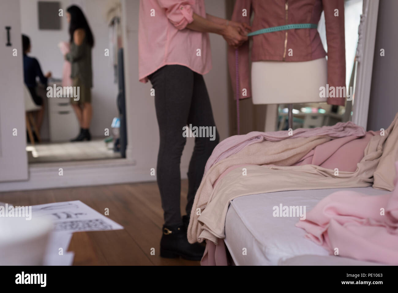 Fashion designer measuring the fabric on dressmakers model in the ...