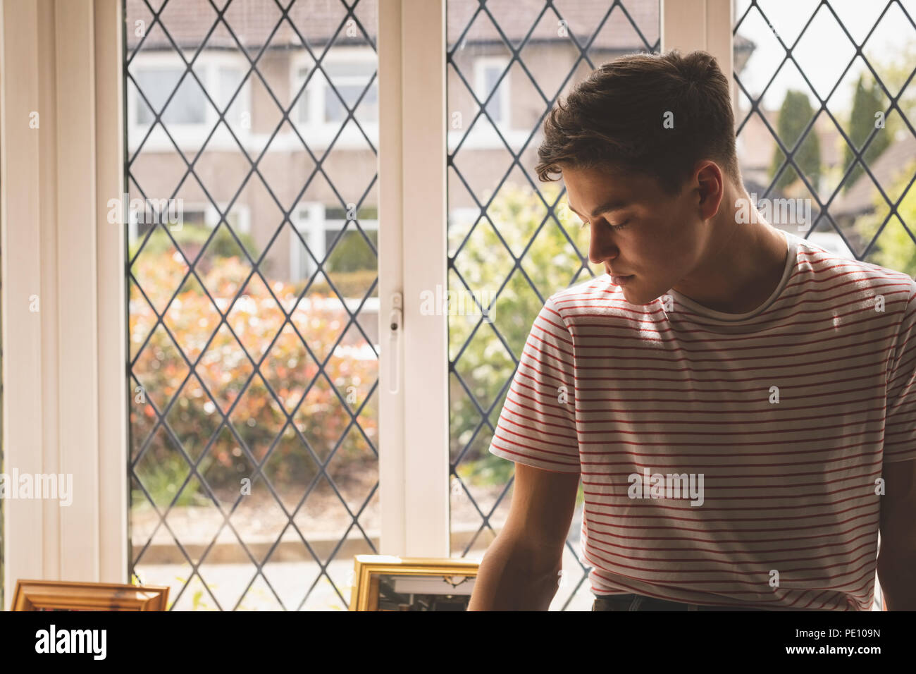 Man sitting on window seat at home Stock Photo - Alamy