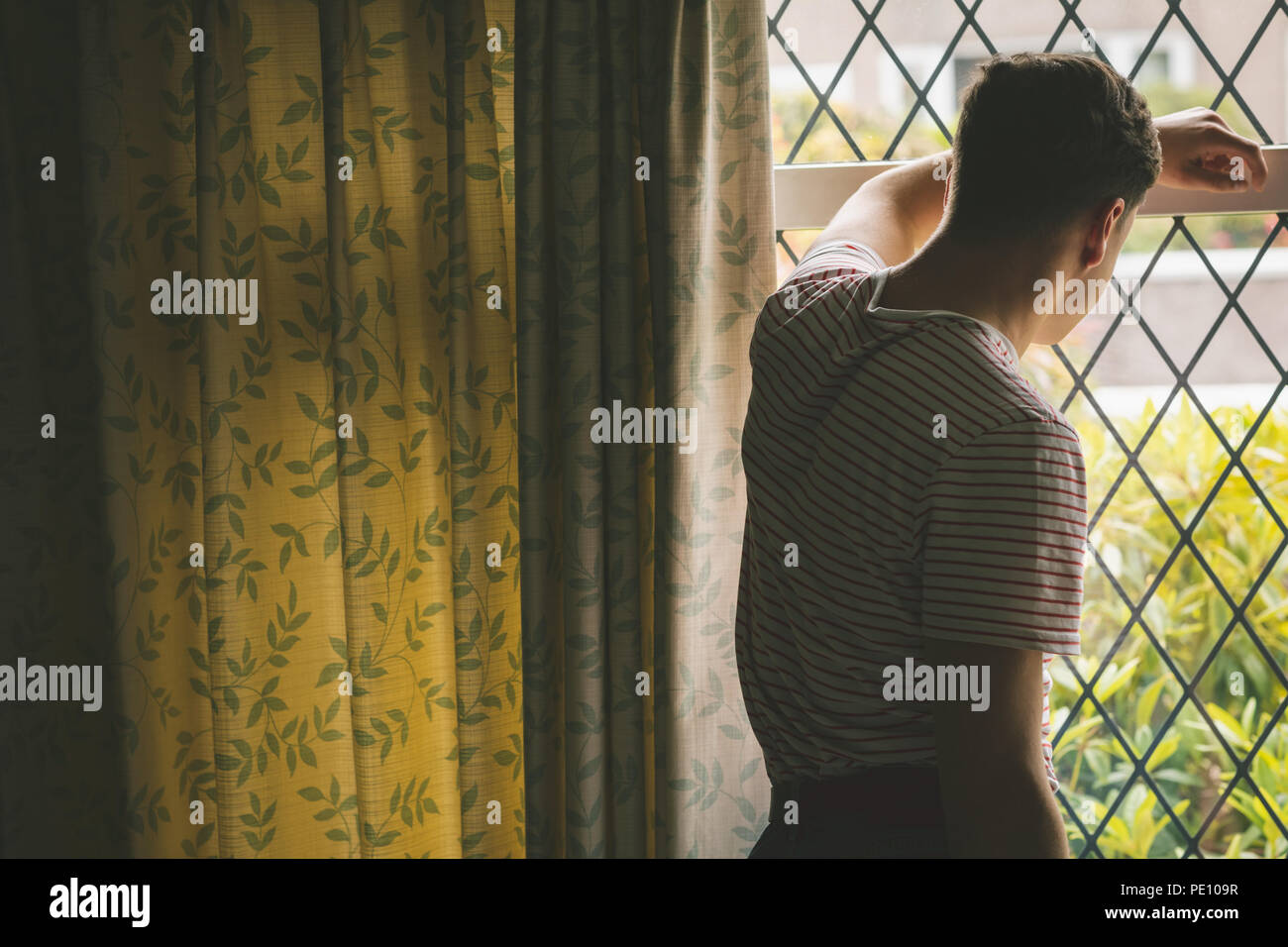 Man looking through window at home Stock Photo - Alamy