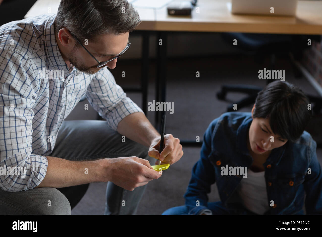 Male executive writing on sticky notes during discussion Stock Photo ...
