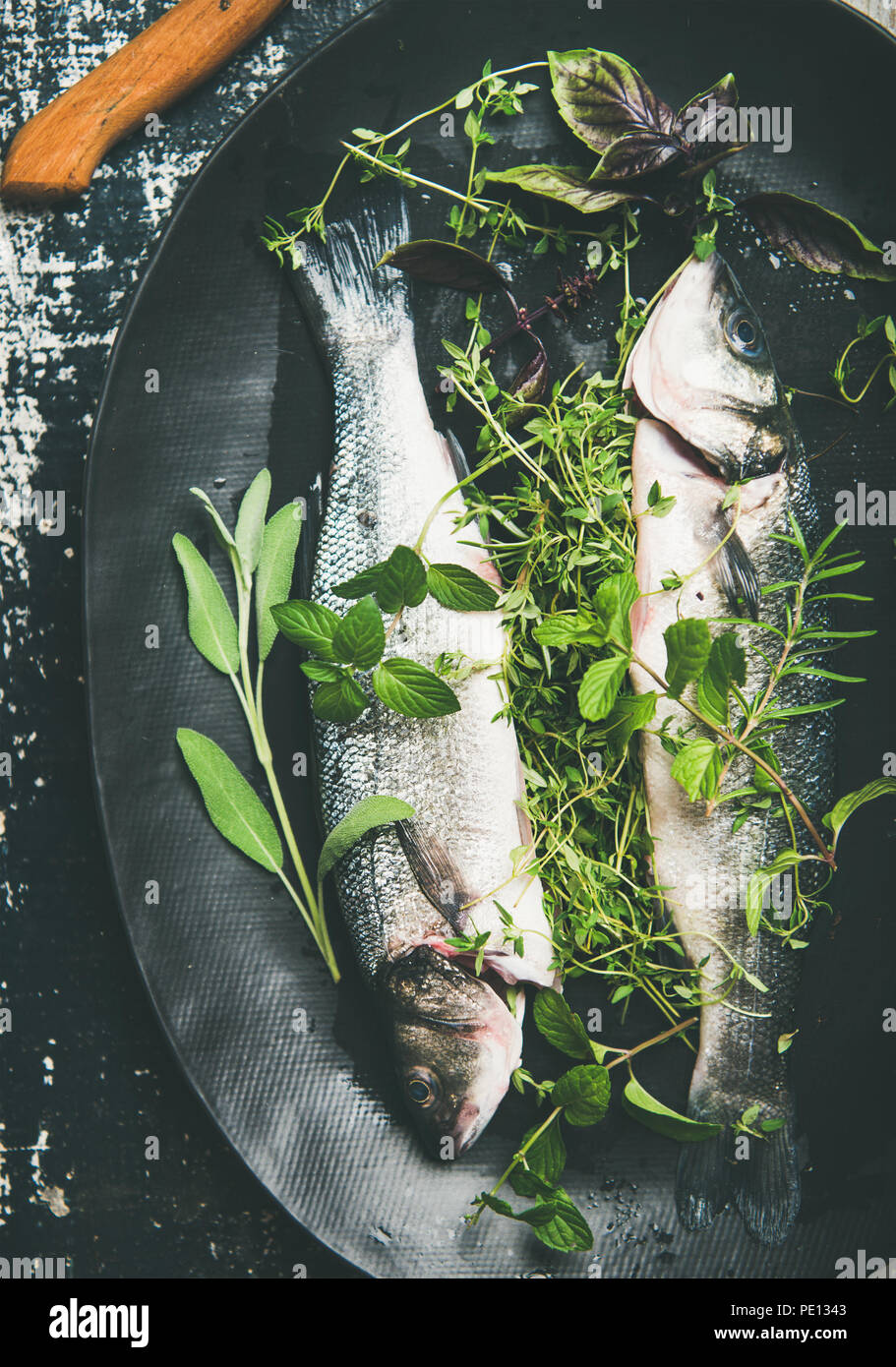 Flat-lay of raw uncooked sea bass fish with herbs Stock Photo - Alamy