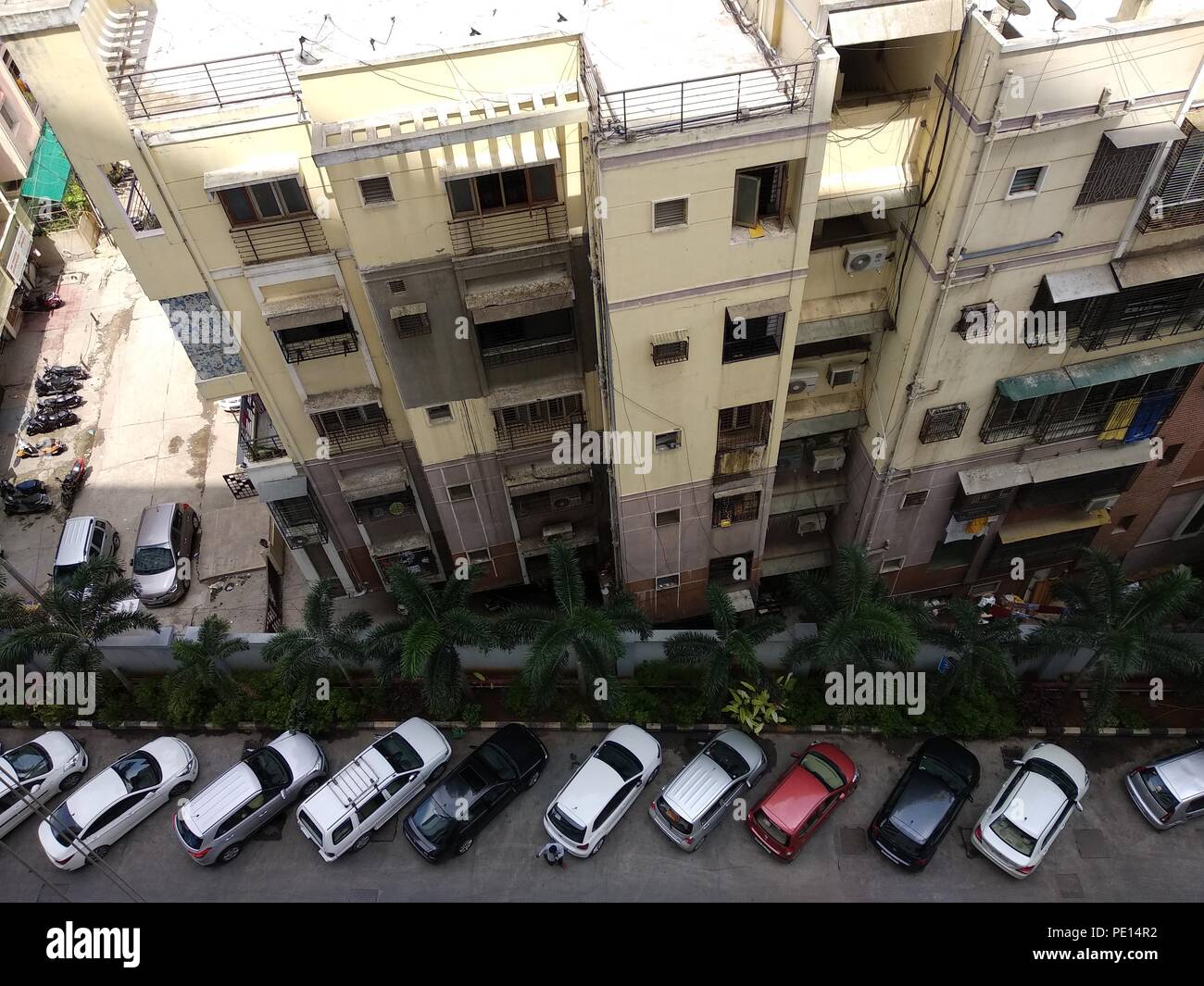 Top down shot of an apartment building complex with cars lined up at ...