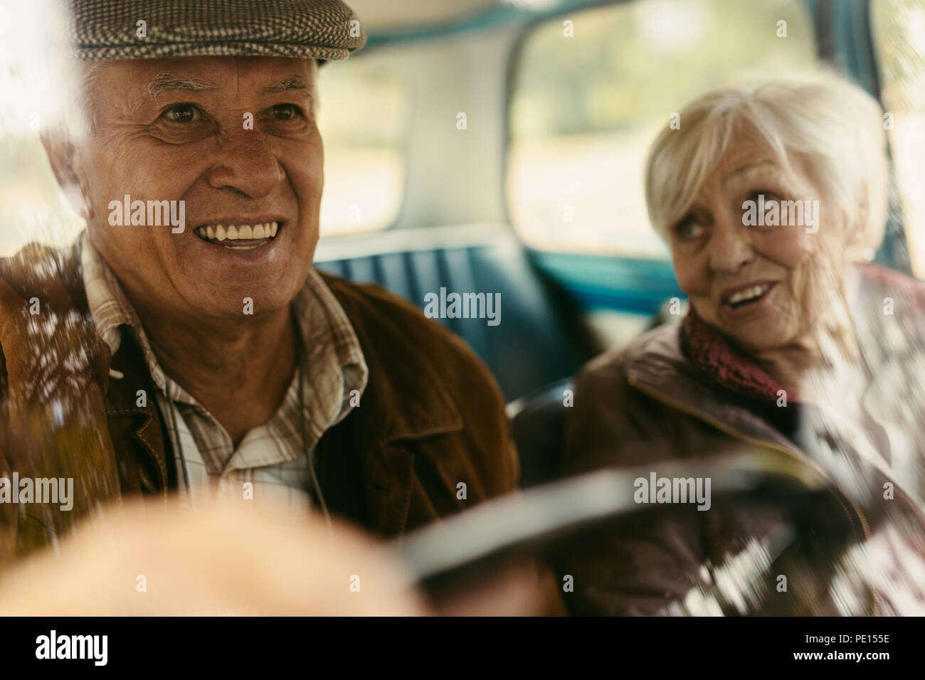 Smiling senior man driving a car with woman on passenger seat. Happy ...