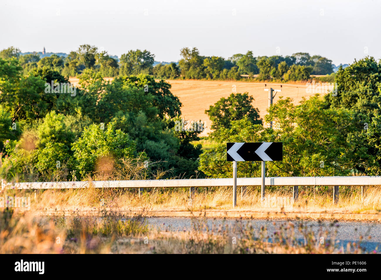 Sharp turn directional sign on British road over countryside rural ...