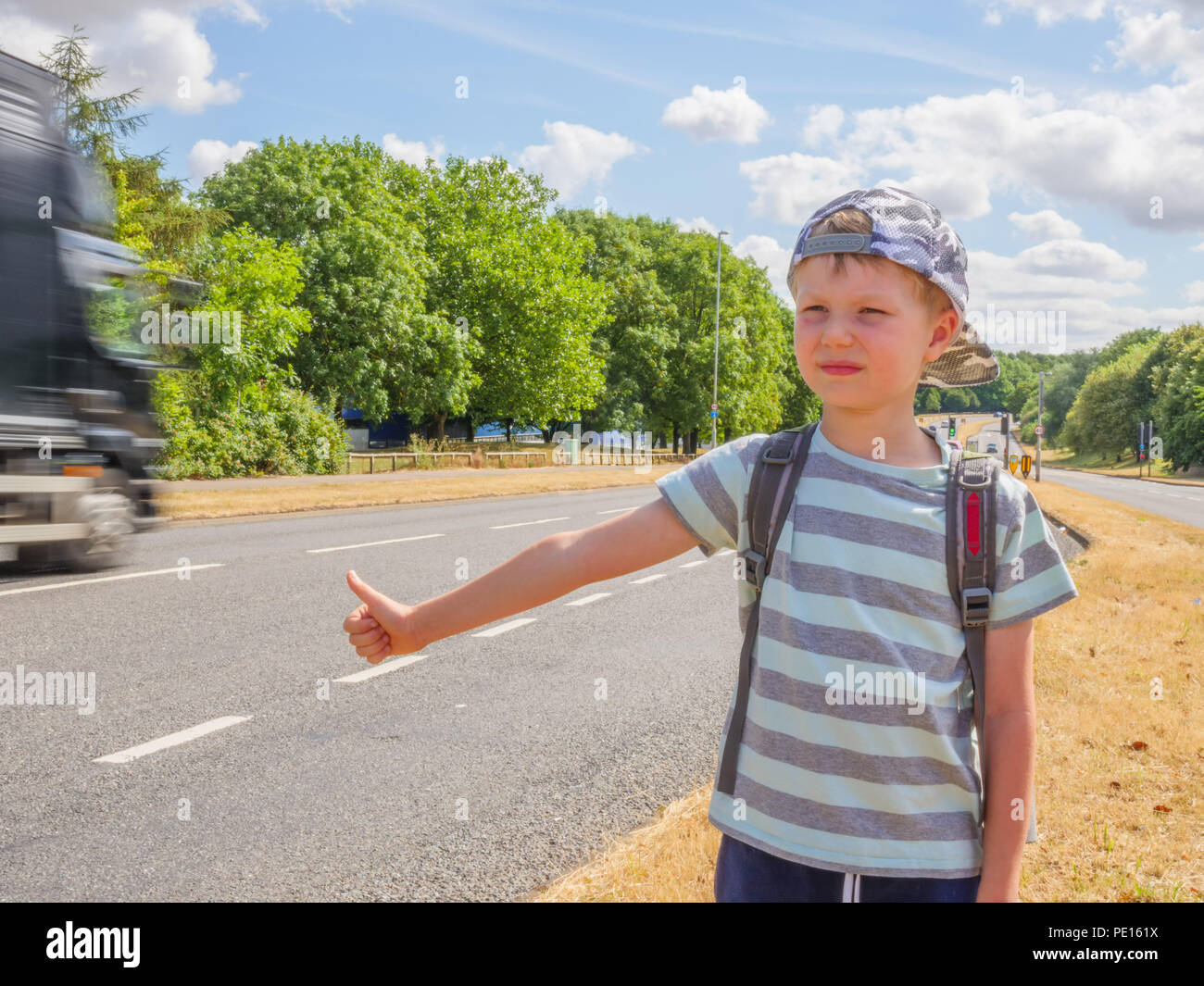 Day view little child boy traveller with backpack catching car on UK ...