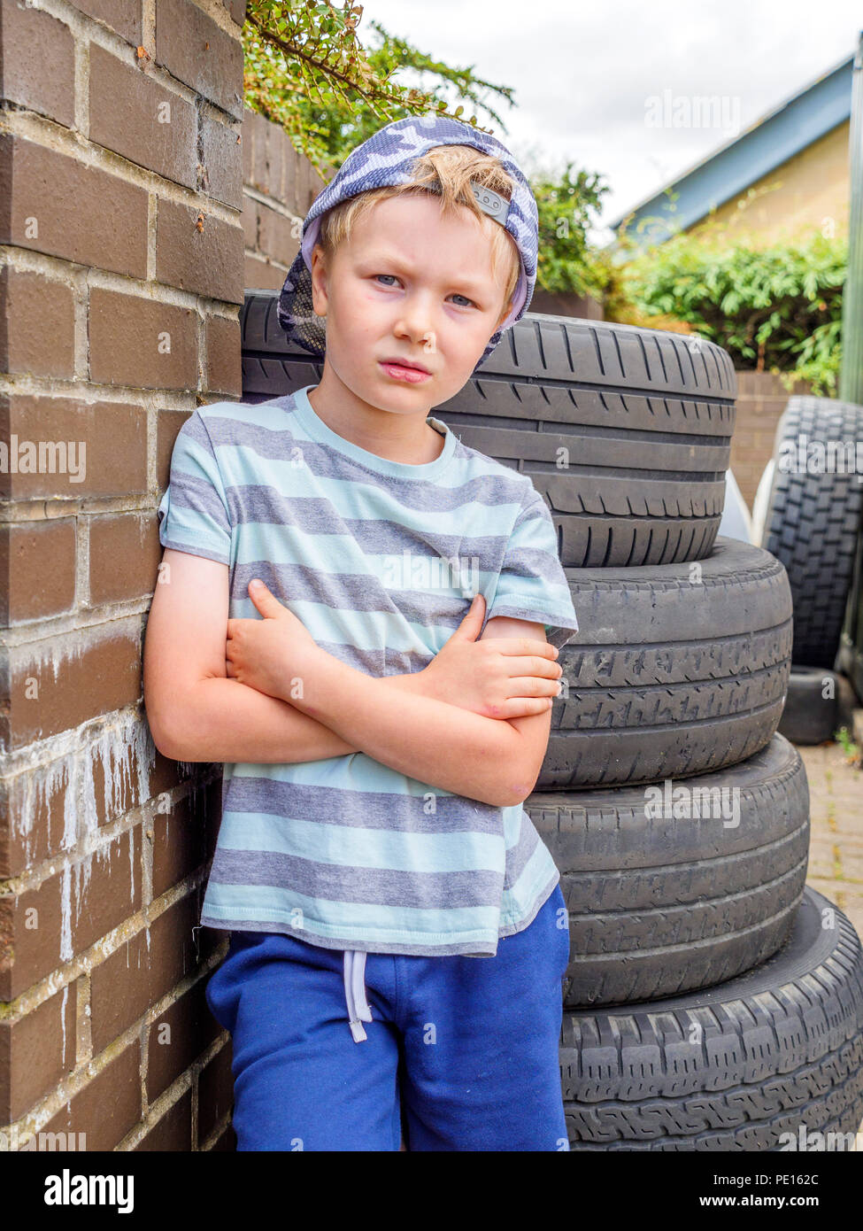 Day view cute little child boy posing next to stack of used tyres over ...