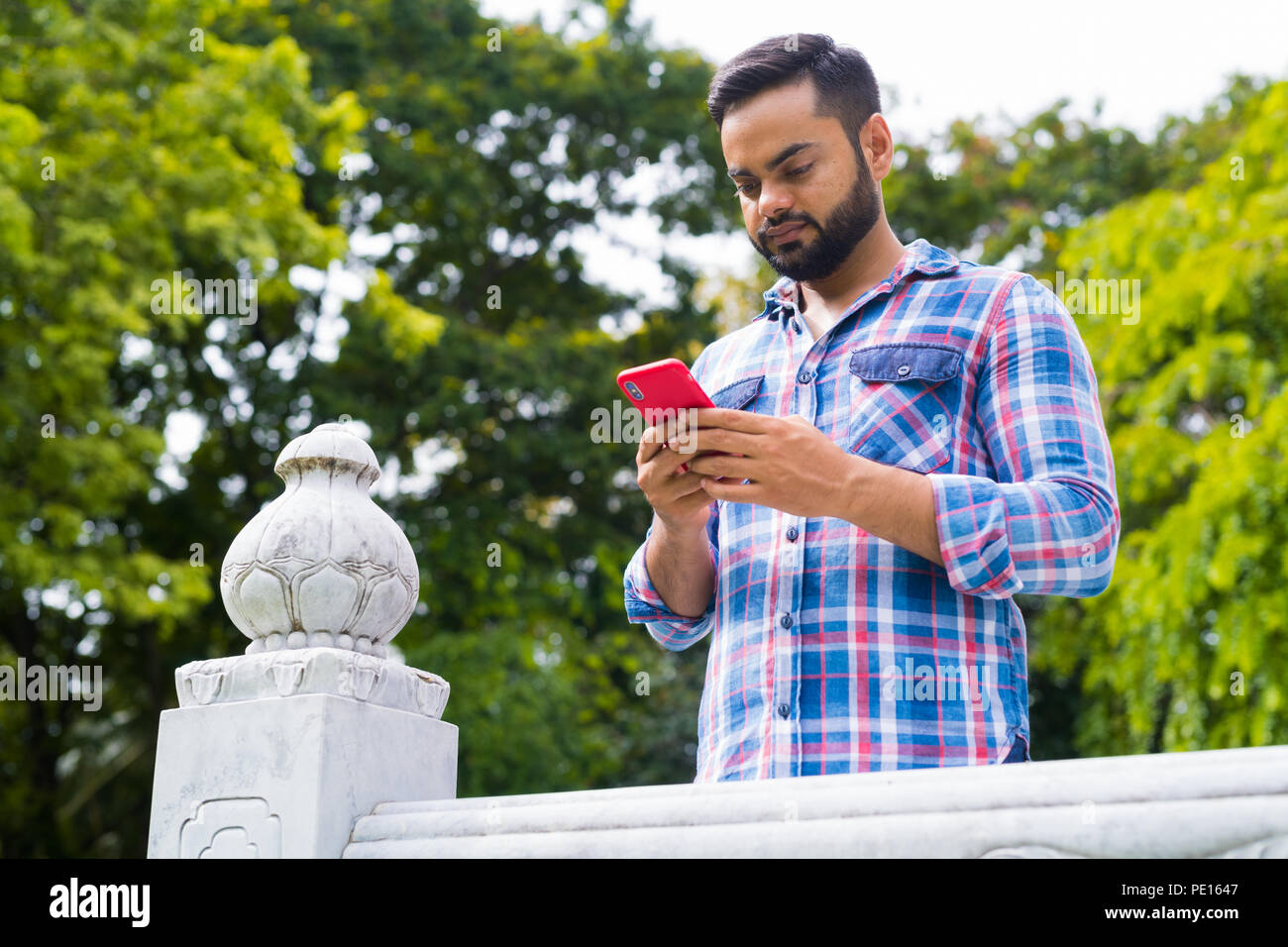 Young Handsome Indian Man In Park Using Mobile Phone Stock Photo - Alamy