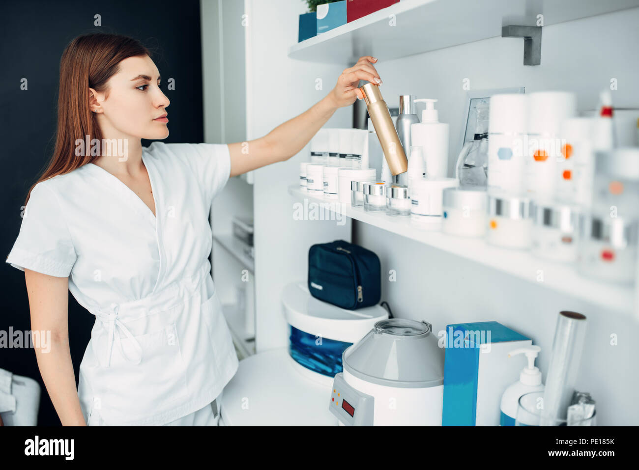Young female beautician with bottle of cream in hands, cosmetology ...