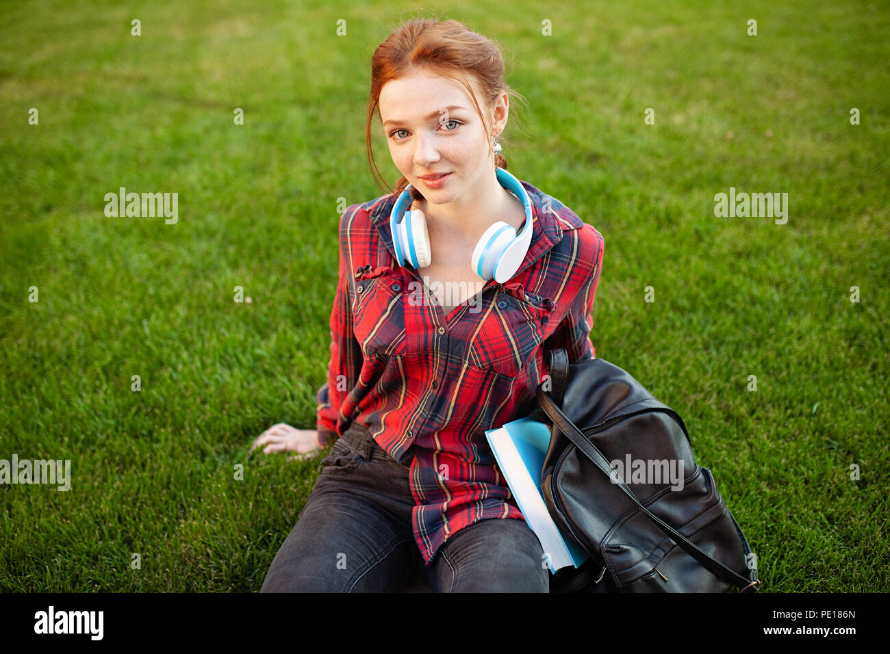 A beautiful red-haired student with freckles is dressed in a red ...