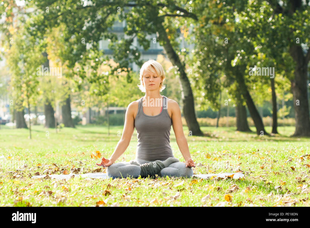 Beautiful woman exercising yoga outdoor.Ardha Padmasana/Half-lotus pose ...