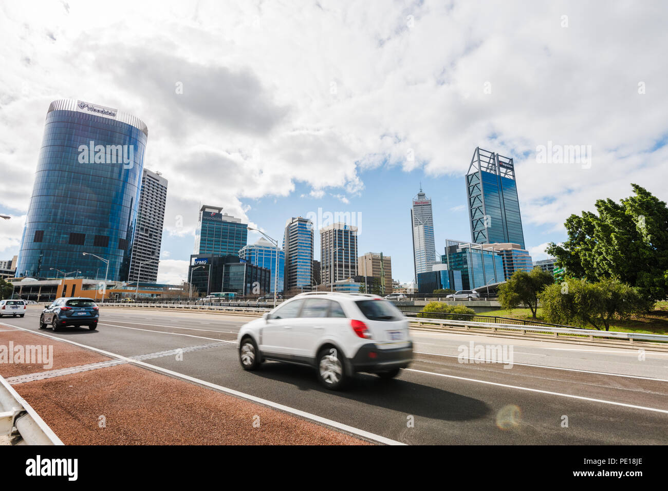Skyscrapers of the financial district with cars rushing by on a highway ...
