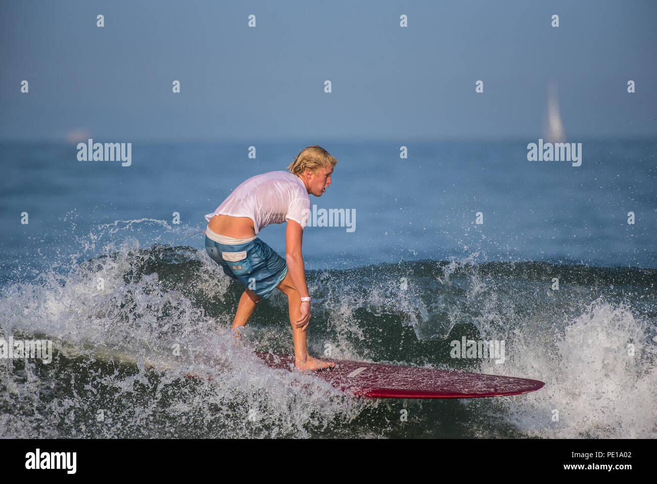 Stylish longboarder in traditional crouch in only trunks and t-shirt ...
