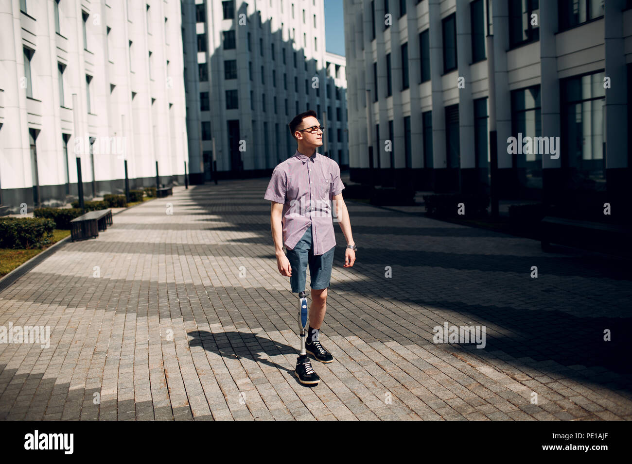 Disabled young man with foot prosthesis walks along the street Stock ...