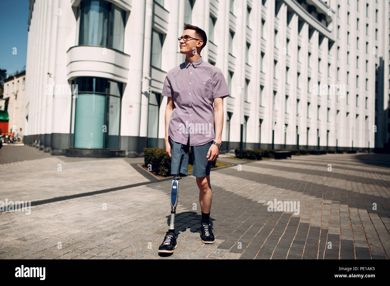 Disabled young man with foot prosthesis walks along the street Stock ...