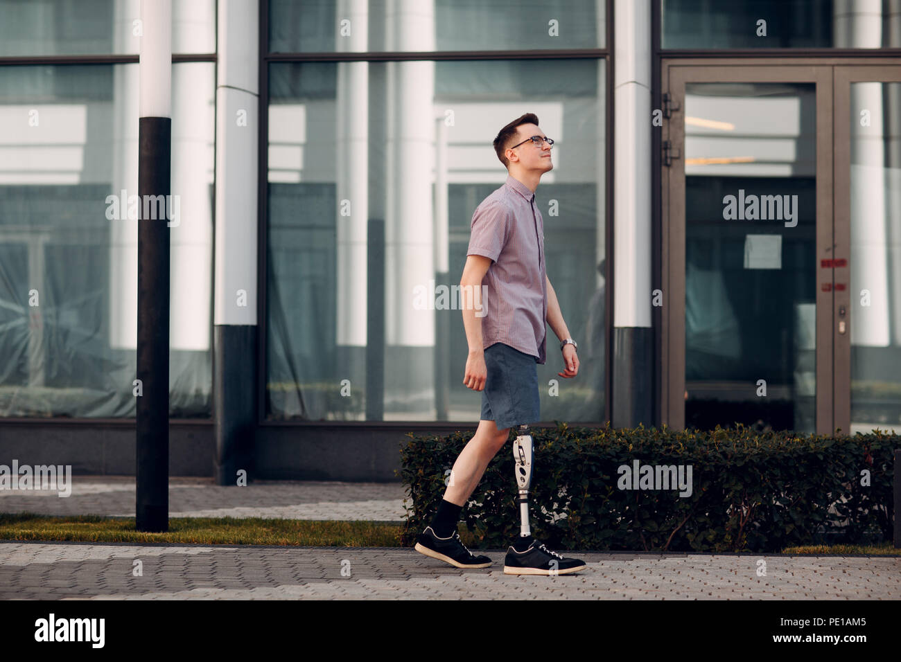 Disabled young man with foot prosthesis walks along the street Stock ...
